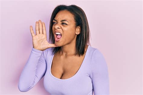 캐주얼 옷을 입은 젊은 아프리카계 미국인 소녀가 손을 입에 대고 소리를 지르며 소리를 질렀습니다 통신 개념입니다 무료 사진