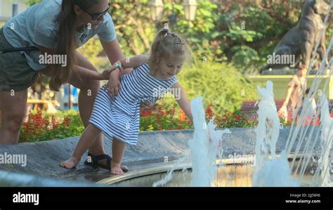 Mom Holds Smiling Little Daughter Playing With Splashes Of Water In The
