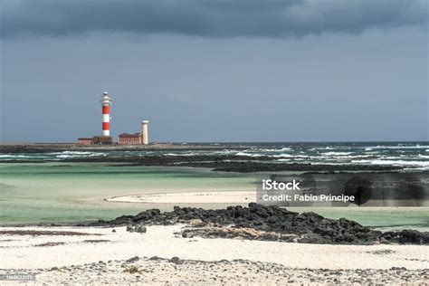 토스톤 등대 엘 코티요 푸에르테벤투라 카나리아 섬 구름이있는 하늘 스페인과 아름다운 풍경 이국적인 휴가에서 엽서 하얀 모래와 녹색 바다 물 라빅 검은 바위 0명에 대한 스톡