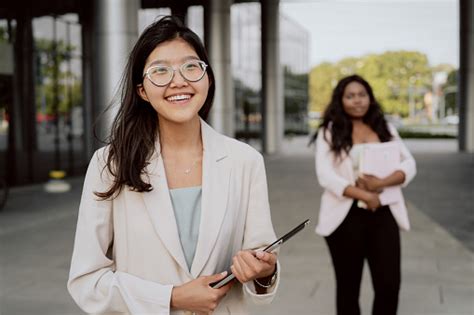 사무실에서 작업의 끝 동료는 회사 건물에서 외부 로 이동 갈색 머리 미소와 안경에 아시아 기능을 가진 젊은 기업 사람들 여성은 경력에 만족 손에 태블릿을 보유 20 24세에