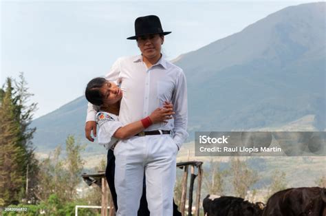 원주민 문화의 전통 의상을 입은 원주민 남성이 화산을 배경으로 한 시골 환경에서 아내를 다정하게 포옹합니다 그의 표정은 따뜻함과