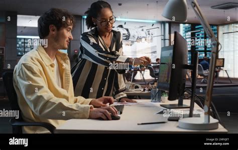 Caucasian Male Game Designer Using Desktop Computer With 3d Modelling Software And Talking To