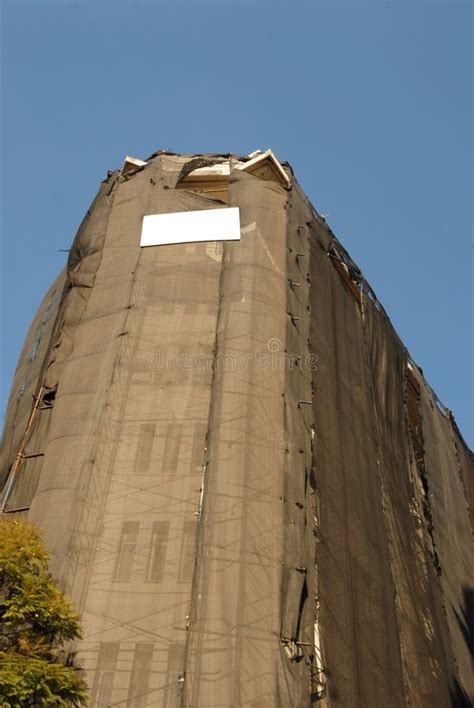 scaffolding and netting covering the facade of a tall building being