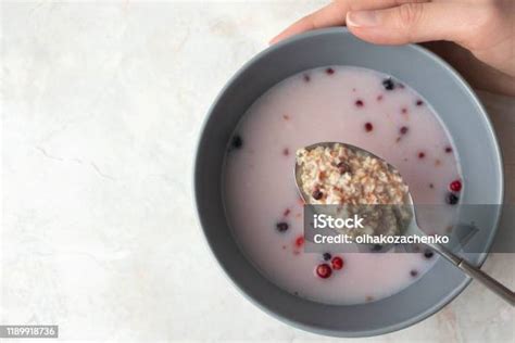 복사 공간이있는 대리석 테이블 배경에서 아침 식사로 회색 그릇에 귀리 베리 및 우유를 넣은 클로즈업 숟가락 가정 생활에 대한