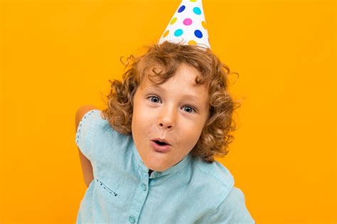 축제 모자를 쓴 유럽의 빨간 머리 곱슬 거리는 소년이 노란색 배경에 카메라를 찡그리고 T 셔츠에 대한 스톡 사진 및 기타 이미지 T 셔츠 곱슬 머리 구매 Istock