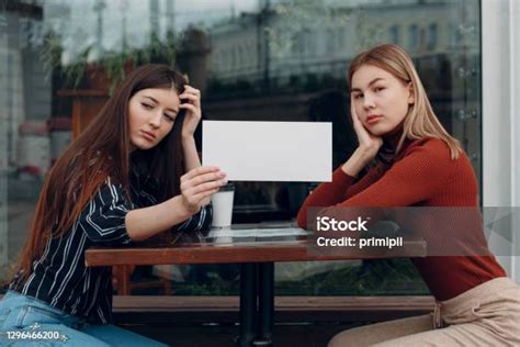 손에 백서를 들고 여자 길거리 카페에서 테이블에서 이야기하는 두 여성 빈 공간이 있는 흰색 빈 템플릿 시트입니다 20 24세에 대한 스톡 사진 및 기타 이미지 Istock