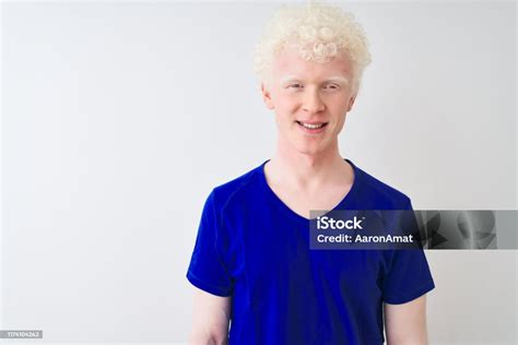 젊은 알비노 금발 남자는 얼굴에 행복하고 시원한 미소와 고립 된 흰색 배경 위에 서 파란색 캐주얼 티셔츠를 입고 운이 좋은 사람