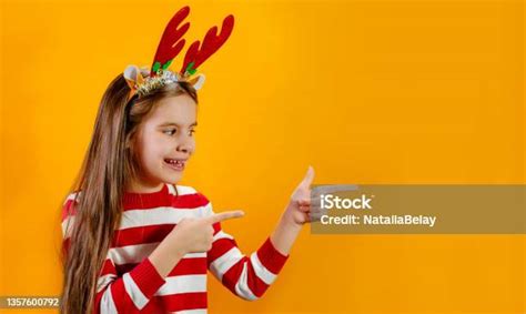 사슴 뿔과 긴 머리를 가진 귀여운 소녀 아이는 노란색 배경에 광고와 텍스트를위한 빈 공간을 가리킵니다 판매 휴일 감정 개념 4 5세에 대한 스톡 사진 및 기타 이미지