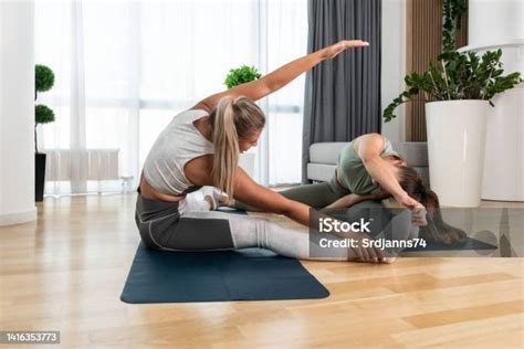 두 명의 젊은 동료 룸메이트 친구 또는 레즈비언 커플이 행복하고 건강한 삶을위한 편안한 호흡 운동으로 아파트에서 근육을 스트레칭하는 운동을 함께 운동합니다 2명에 대한 스톡