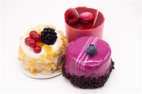 흰색 배경에 세 개의 케이크 라즈베리를 곁들인 밝은 빨간색 마카롱 위에 마카롱 아몬드 꽃잎을 곁들인 크림 케이크 레드 건포도와