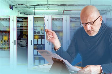 배전반의 배경에 있는 엔지니어 한 남자가 배전반의 회로를 살핀다 전기 기술자의 일 엔지니어링 작업 사무실에 전기를 공급합니다 45 49세에 대한 스톡 사진 및 기타 이미지
