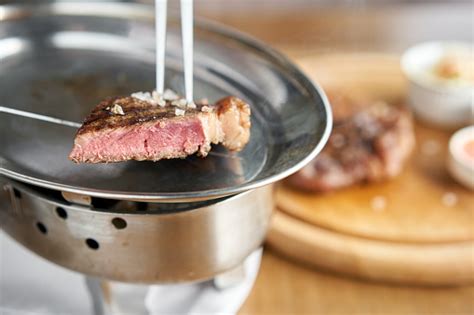 웨이터는 절인 양배추와 두 개의 소스와 함께 구운 스트립 백 스테이크 접시를 들고있다 스트립 스테이크 또한 뉴욕 스트립이라고 나무 판에서 봉사 바비큐 레스토랑 메뉴 갈비