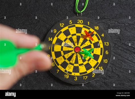 Hand Throws A Dart Into A Dart Board On Black Concrete Stock Photo Alamy