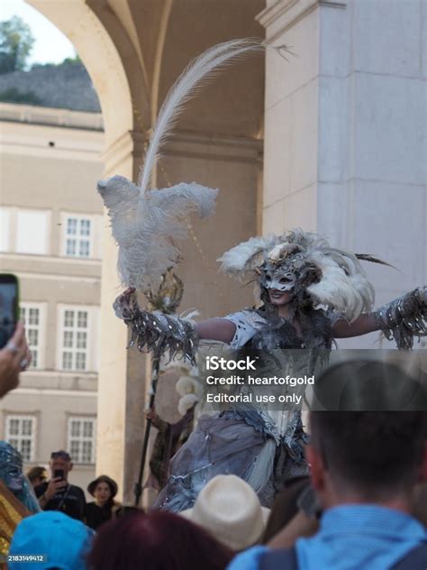 오스트리아 잘츠부르크 2024년 8월 31일 큰 깃털이 달린 투구와 화려한 액세서리가 달린 정교한 축제 의상을 입은 개인이 축하 행사나 행사 중 석조 구조물 앞에서 포즈를