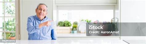 얼굴에 행복하고 자연스러운 표정으로 손과 손가락으로 가리키는 얼굴의 미소와 함께 집에서 잘 생긴 선배의 넓은 각도 관점 가리키기에 대한 스톡 사진 및 기타 이미지 Istock