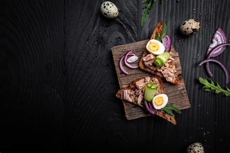 참치 맛있는 건강 식품을 곁들인 토스트 통조림 참치와 오이가 들어간 샌드위치 어두운 배경에 메추라기 달걀과 양파 톱 뷰 참치 해산물에 대한 스톡 사진 및 기타 이미지