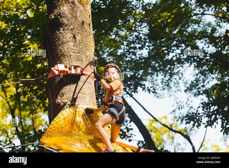 the concentrated girl carefully overcomes obstacles in the rope park