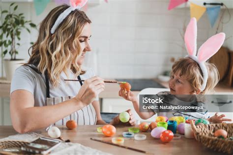 매력적인 여자와 토끼 귀에 그녀의 두 살짜리 아들이 부엌의 테이블에 앉아 페인트와 부활절 달걀페인트 2 3 살에 대한 스톡 사진 및 기타 이미지 Istock