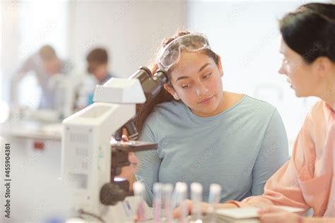 Female Teacher And Girl Babe Conducting Scientific Experiment At Microscope In Laboratory