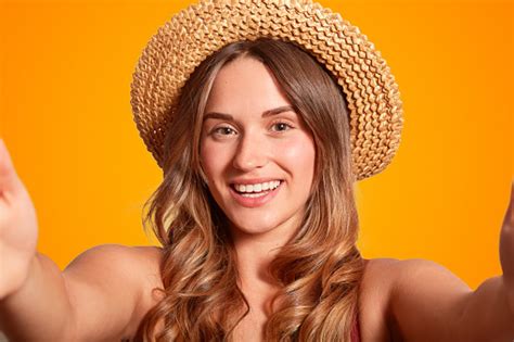 건강 한 순수 피부 Toothy 미소와 아름 다운 웃는 여자의 샷까지 가까운 우아한 밀 짚 모자를 착용 Selfie 초상화 포즈에 대 한 오렌지 배경 수 있습니다 사람 감정