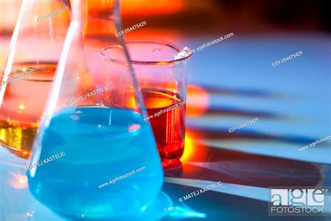 illuminated laboratory flask filed with colorful chemical solutions