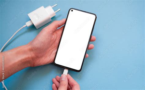 Connecting Charging A Smartphone Via A USB Cable And A Power Supply Unit On A Blue Background