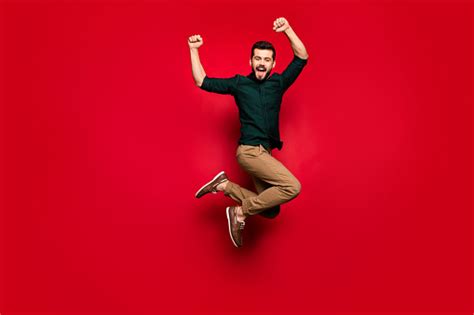 전체 길이 사진 O0f 기쁘게 남자 축하 복권 승리 점프 상승 주먹 비명 예 붉은 색 배경을 통해 고립 된 갈색 바지 바지를 착용 남자에 대한 스톡 사진 및 기타 이미지