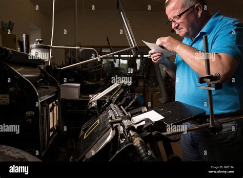 Mature Male Printer Inspecting Paper For Printing Machinery In Printing Press Workshop Stock