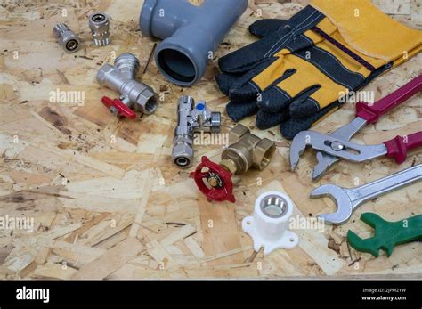 Plumbing Tools Parts Pipeline Components And Gloves On The Background Of A Construction Osb
