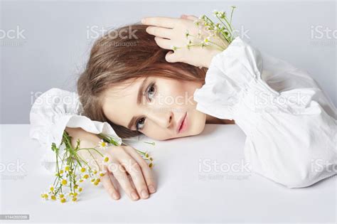 곱슬 금발 낭만적 인 모습 아름 다운 눈 손에 흰 야생화 소녀 흰 빛 드레스와 곱슬 머리 흰색 배경 순도와 무죄에 꽃을 가진 여자의 초상화 가정 생활에 대한 스톡 사진 및