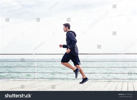 Side View Portrait Of A Sports Man Running Near The Sea