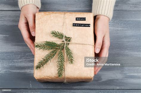 파란색 나무 배경에 나무 가지와 크래프트 에코 선물 상자를 들고 여자의 손 최고 보기 휴일 선물 개념 개념에 대한 스톡 사진 및 기타 이미지 Istock