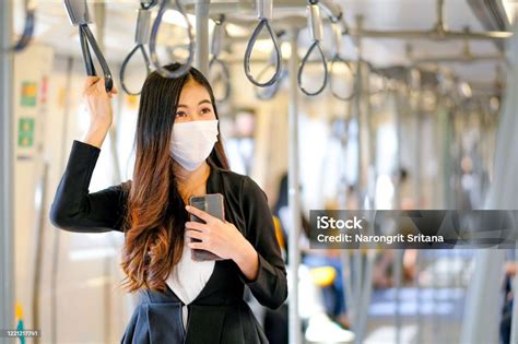 위생 마스크와 아름 다운 비즈니스 여자의 초상화 휴대 전화를 잡고 서 서 있는 핸드레일을 하늘 기차에 들고 도 오른쪽을 본다