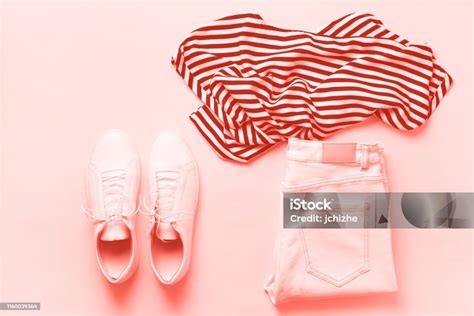 여성 흰색 운동화와 청바지 카피 공간이있는 트렌디 한 산호 색상 배경의 스트라이프 티셔츠 맨 위 보기 여름 패션 캡슐 옷장 컨셉