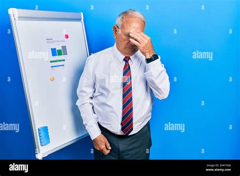 Senior Man With Grey Hair Standing By Business Blackboard Tired Rubbing
