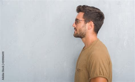 Handsome Young Man Over Grey Grunge Wall Wearing Glasses Looking To