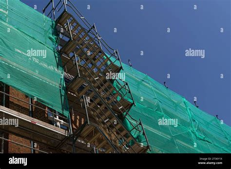 Scaffolding For Renovation Of Building Facades Covered With Protective Green Mesh Building