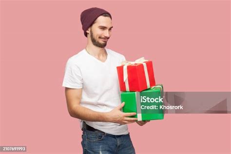 교활하고 웃는 수염을 기른 남자가 선물 상자를 들고 서서 교활한 표정으로 카메라를 바라보고 있습니다 20 24세에 대한 스톡 사진 및 기타 이미지 Istock
