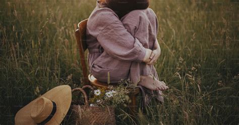 리넨 드레스를 입은 아름다운 여자가 소박한 의자에 앉아 여름 초원에서 꿈을 꾸고 있다 분위기 있는 고요한 순간 일몰에