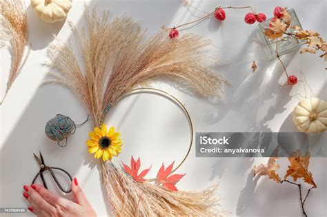 마른 팜파스 풀과 가을 잎으로 말린 꽃 화환을 만드는 손 스웨터에 손을 넣은 손은 장식을 금속 프레임에 묶습니다 0명에 대한 스톡 사진 및 기타 이미지 Istock