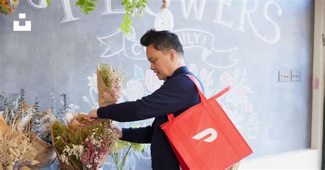 꽃다발 근처에 빨간 쇼핑백을 들고 있는 남자 사진 Unsplash의 무료 남성 이미지