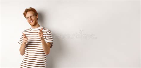 Cool And Sassy Redhead Man With Beard And Glasses Pointing Finger Pistols At Camera And Smiling