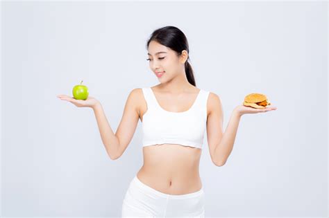 흰색 배경에 고립 된 신선한 샐러드 야채와 햄버거를 선택하는 다이어트와 아름다운 젊은 아시아 여성 슬림 모양 칼로리 영양 및 라이프 스타일 개념으로 체중 감량을위한 제어와