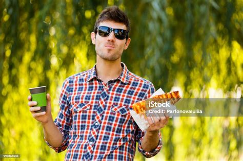 남자 피자를 먹는입니다 쾌활 한 젊은 남자는 공원에 피자 마시는 커피를 먹으십시오 건강에 좋지 않은 음식에 대한 스톡 사진 및 기타 이미지 건강에 좋지 않은 음식