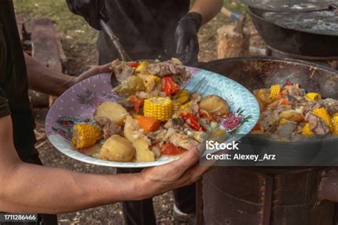 요리사는 주철 가마솥에서 감자와 야채와 함께 튀긴 고기를 접시에 놓습니다 길거리 음식 가마솥에 대한 스톡 사진 및 기타 이미지 가마솥 감자 요리 거리 Istock