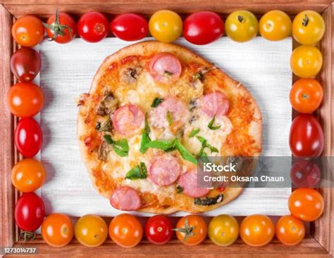 여러 가지 빛깔의 체리 토마토로 장식 된 나무 그림 프레임에 소시지 버섯 치즈를 곁들인 홈메이드 미니 피자 0명에 대한 스톡