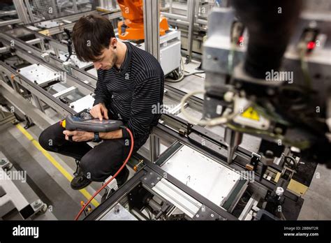 Man Programming Robot In Automotive Industrial Professional Programmer