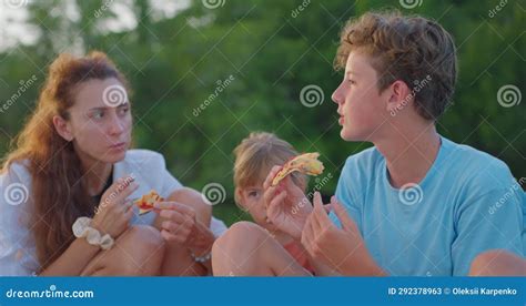 Mom With Her Little Daughter And Teenage Son Eats Pizza Outdoors And