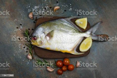 허브 향신료 로즈마리 토마토와 나무 도마와 검은 접시 배경에 레몬 신선한 Pomfret 물고기 원시 검은 Pomfret 물고기 건강한 식생활에 대한 스톡 사진 및 기타