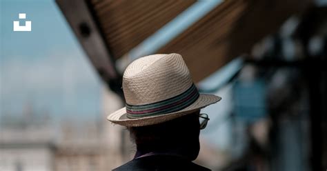 흰 밀짚모자와 검은 셔츠를 입은 남자가 거리를 걷고 있다 사진 Unsplash의 무료 모자 이미지